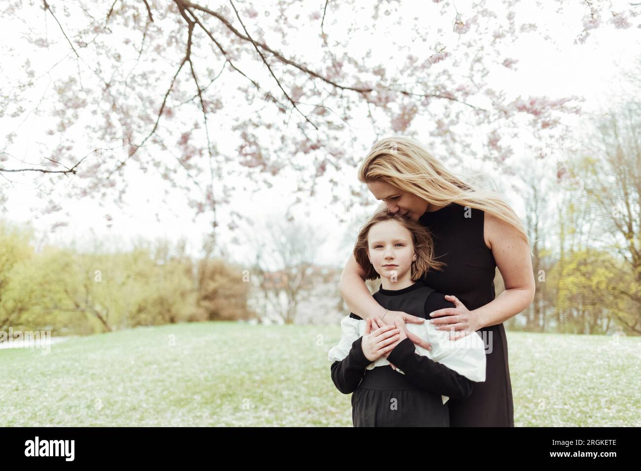 Happy woman with blond hair hugging and kissing girl in black blouse ...