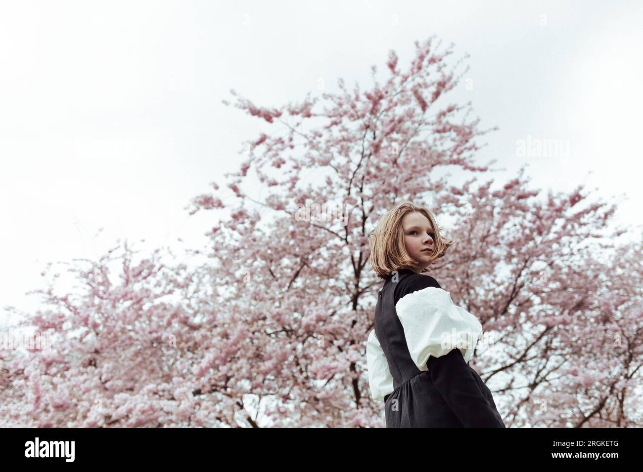 Low angle side view of little girl standing in park near blooming ...