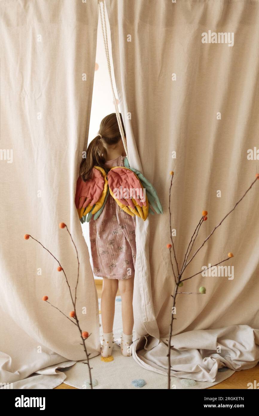 Back view of anonymous girl in casual clothes with colorful mini wing ...