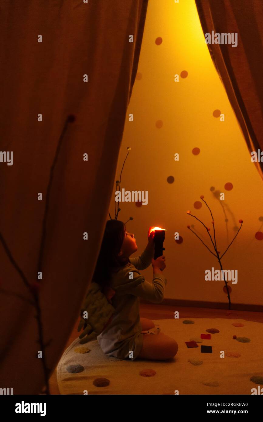 Side view of cute girl in angelic costumes sitting on floor with ...