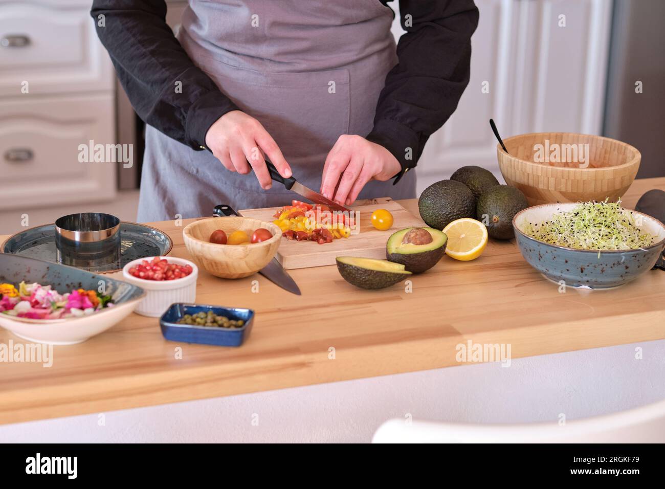 Crop unrecognizable chef cutting tomatoes on chopping board while ...