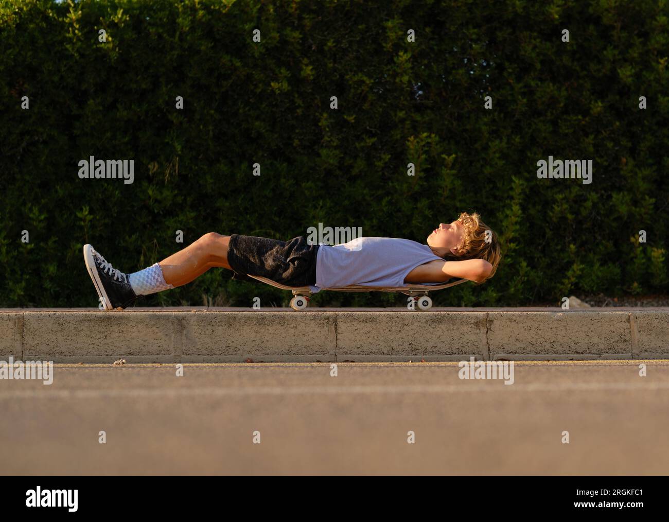 Ground level side view of preteen boy lying on skateboard in street and ...