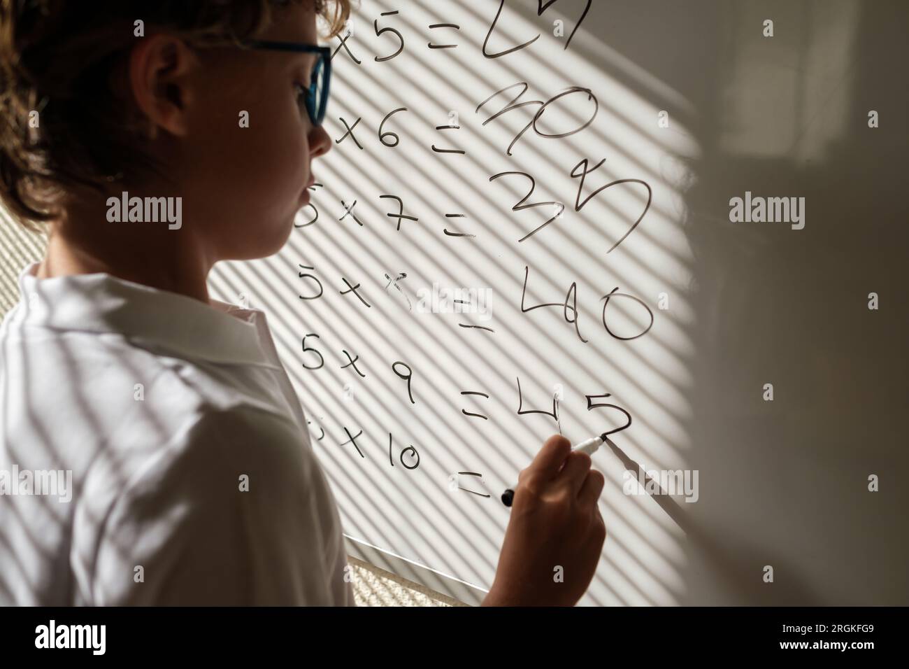 Side view of focused intelligent schoolkid in glasses solving ...