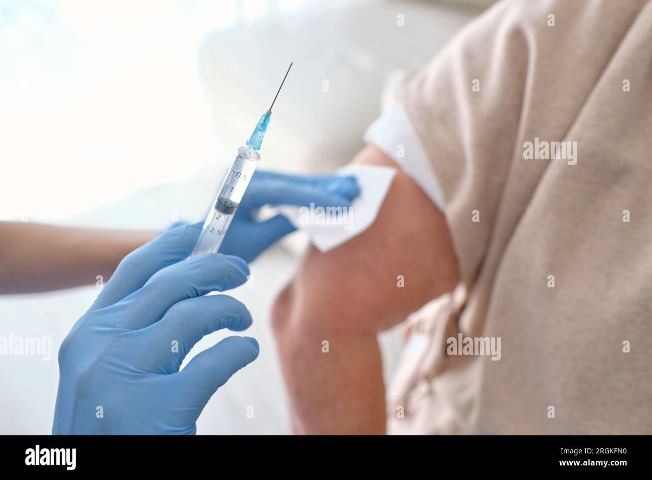 Crop anonymous doctor in sterile gloves with injector touching arm of ...