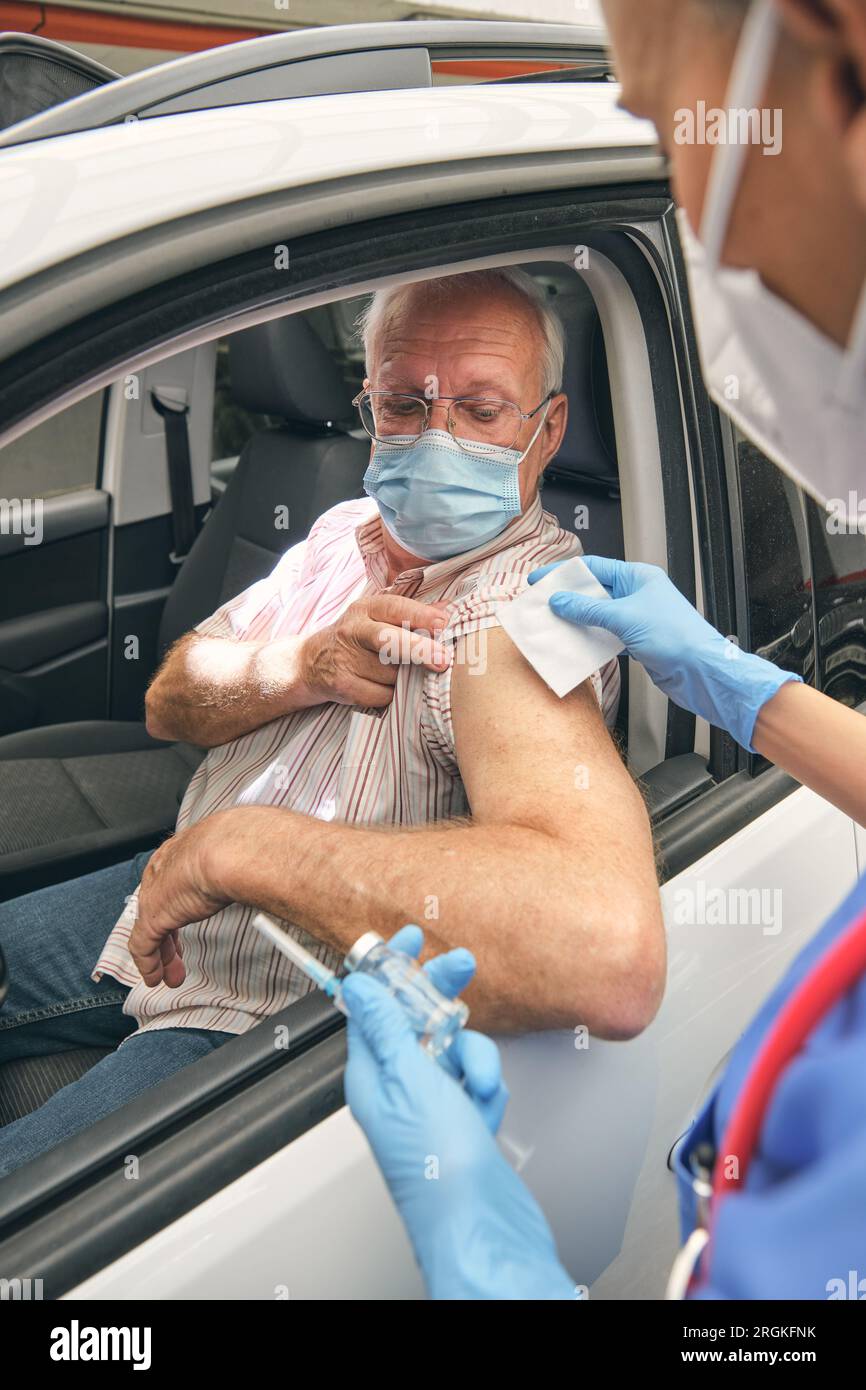 Crop unrecognizable doctor with medical napkin and syringe preparing ...