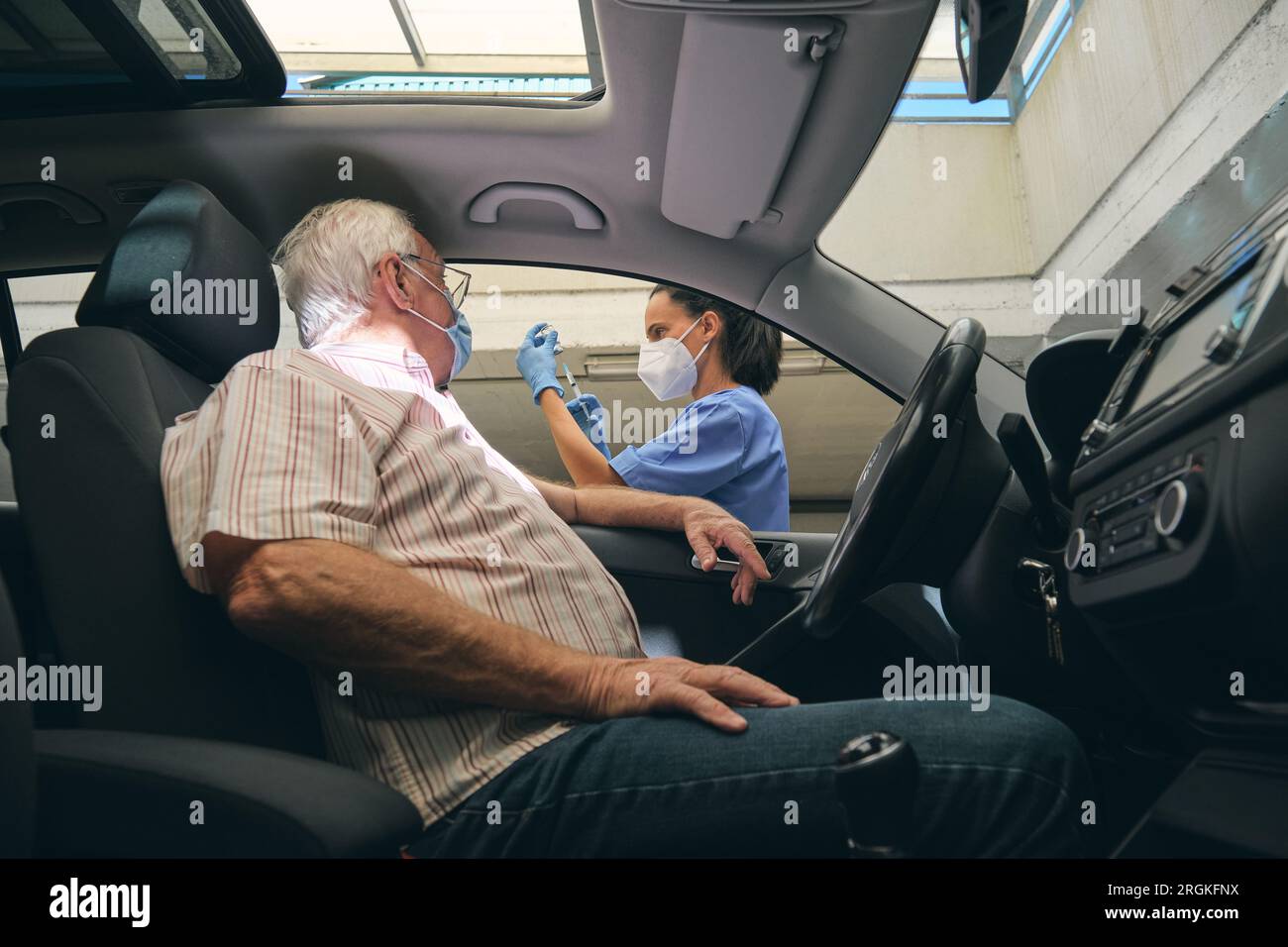 Unrecognizable Elderly Male Patient In Automobile Against Crop Female