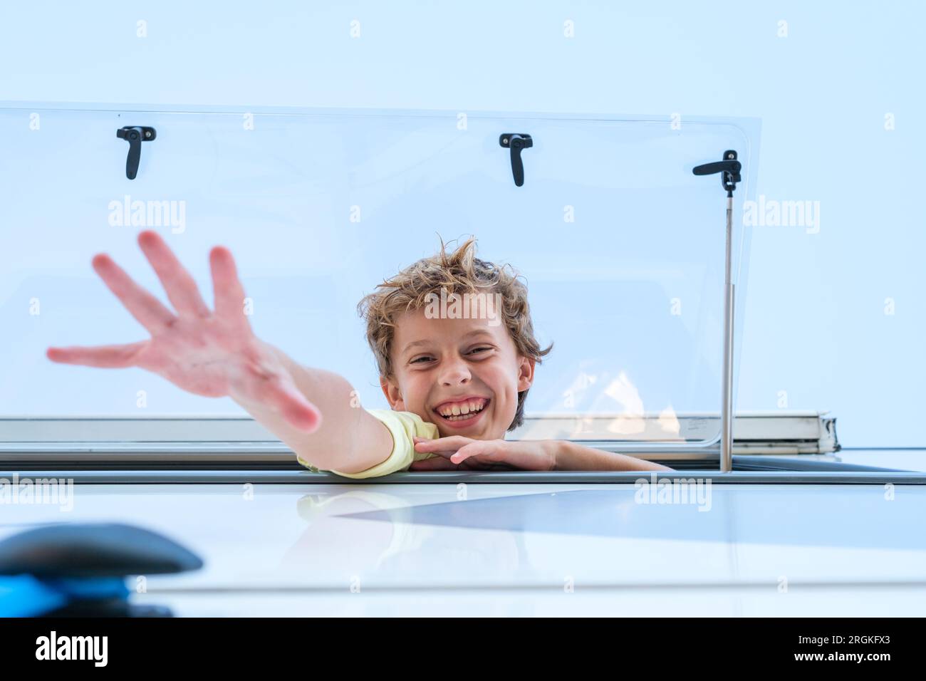 From below cheerful child smiling happily and reaching out camera while ...