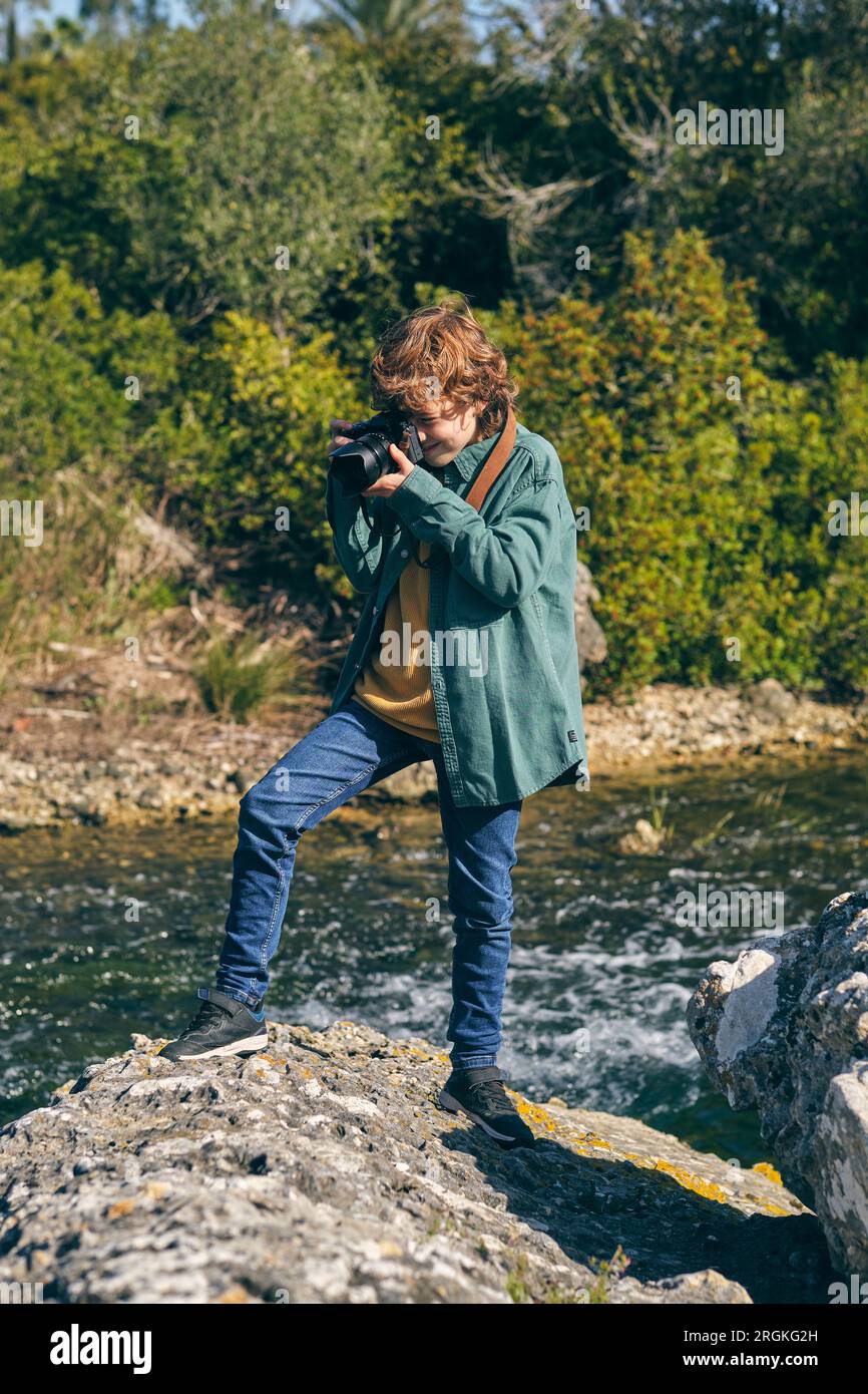 Full body side view of concentrated kid taking picture with ...