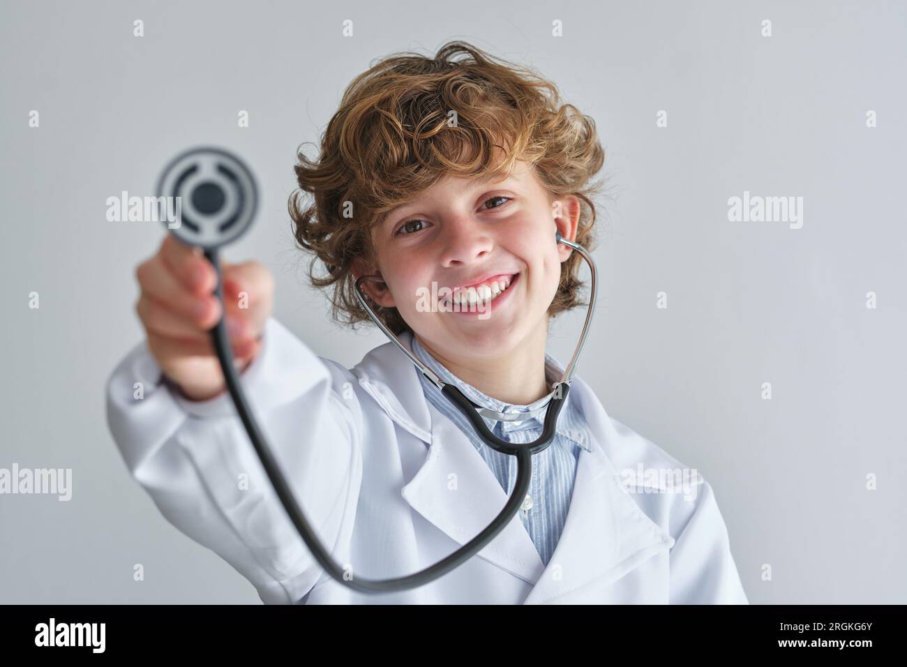 Candid child in medical robe with professional instrument looking at ...