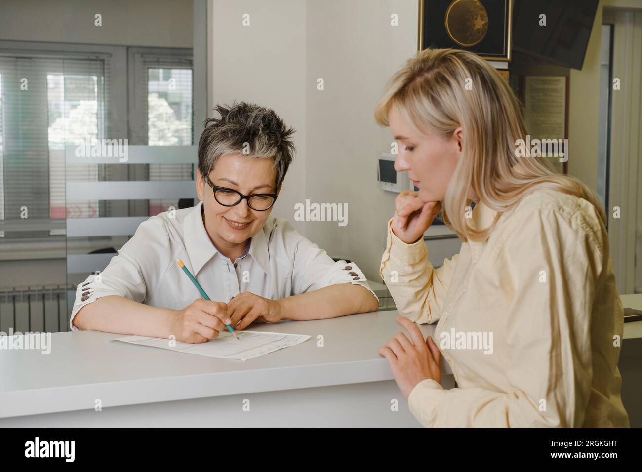 Patient at reception desk of clinic talking about her appointment ...