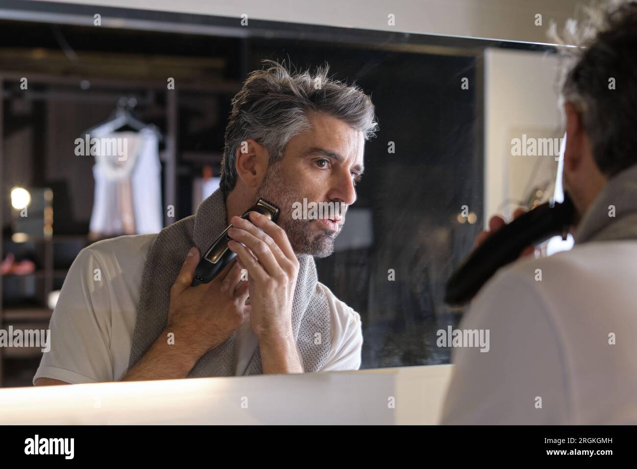 Focused man with gray beard doing morning routine and shaving using ...