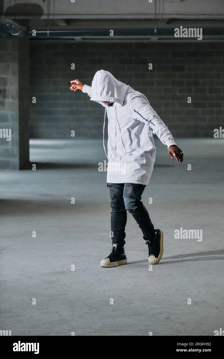 Full length of mysterious male model with face hidden under hood ...