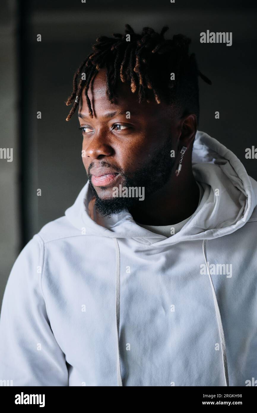 Serious ethnic male model in trendy hoodie and with dreadlocks gazing ...