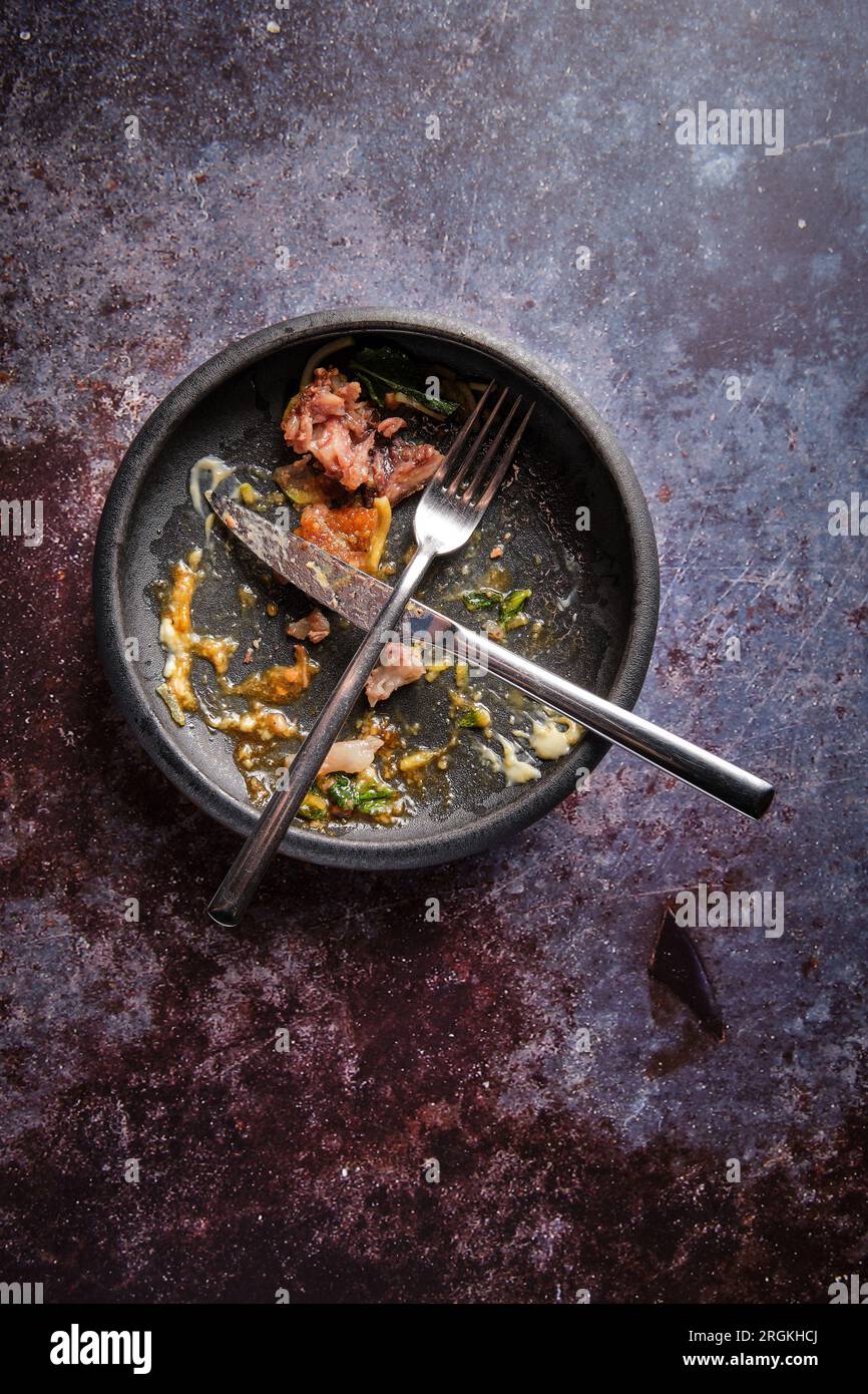 Top view of crossed metal cutlery placed on dirty dark plate on aged ...