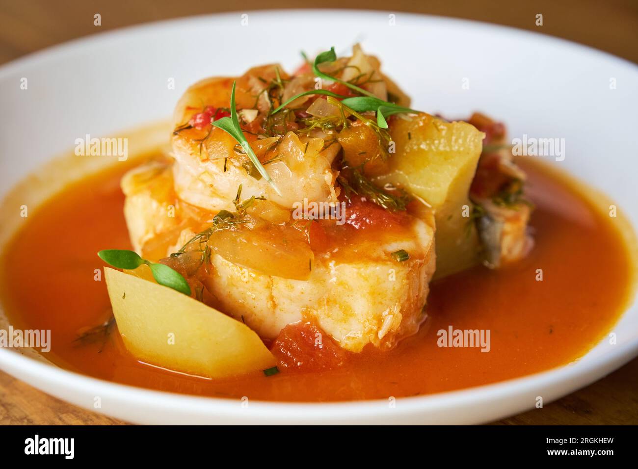 White dish of cod and prawn with potatoes and palm pepper aioli in a ...