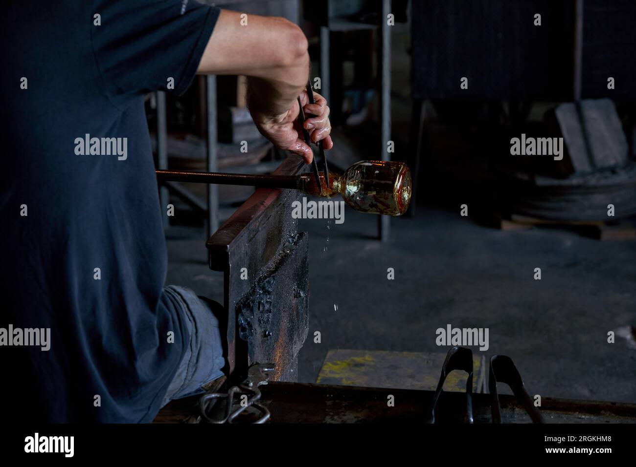 Back view of crop anonymous blower preparing glass using rod and metal ...