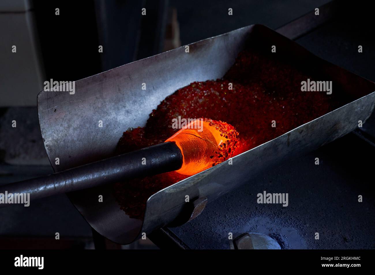 From above of hot glass object on metal blow tube in container during ...