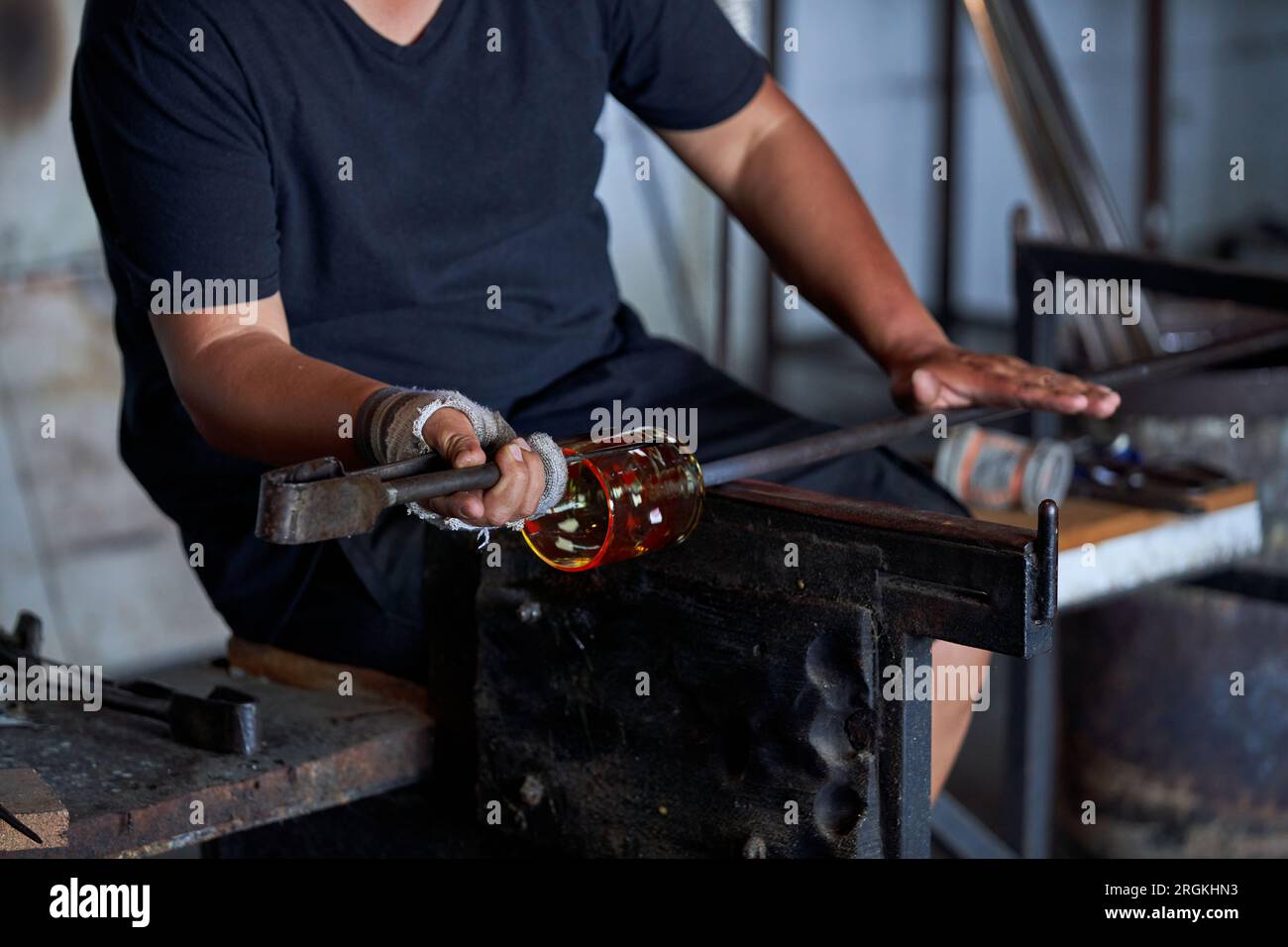 Crop anonymous male artisan with tool shaping melted glass on rod in ...