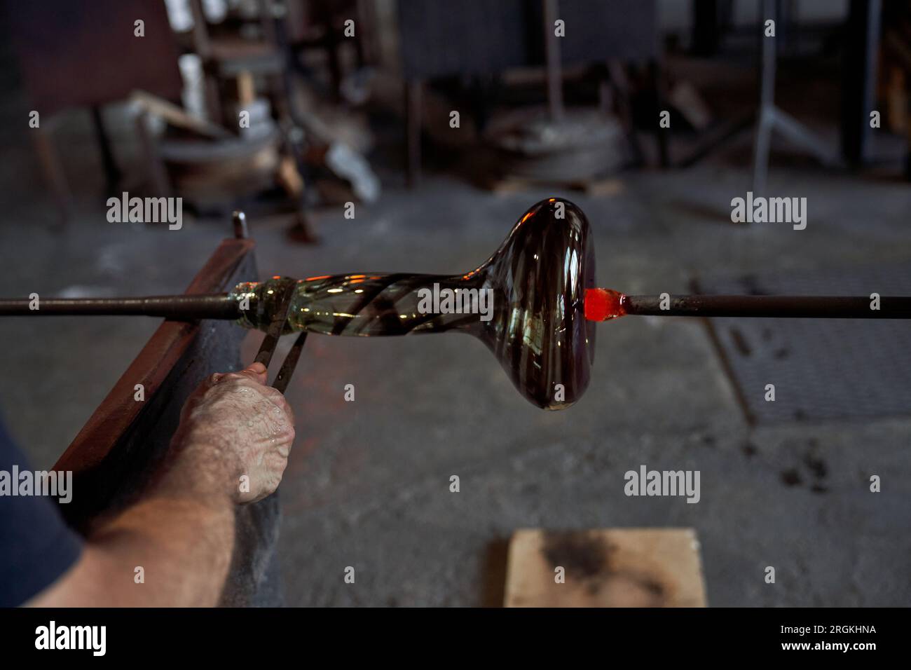 Unrecognizable male glassmith in process of making glass hookah vase ...