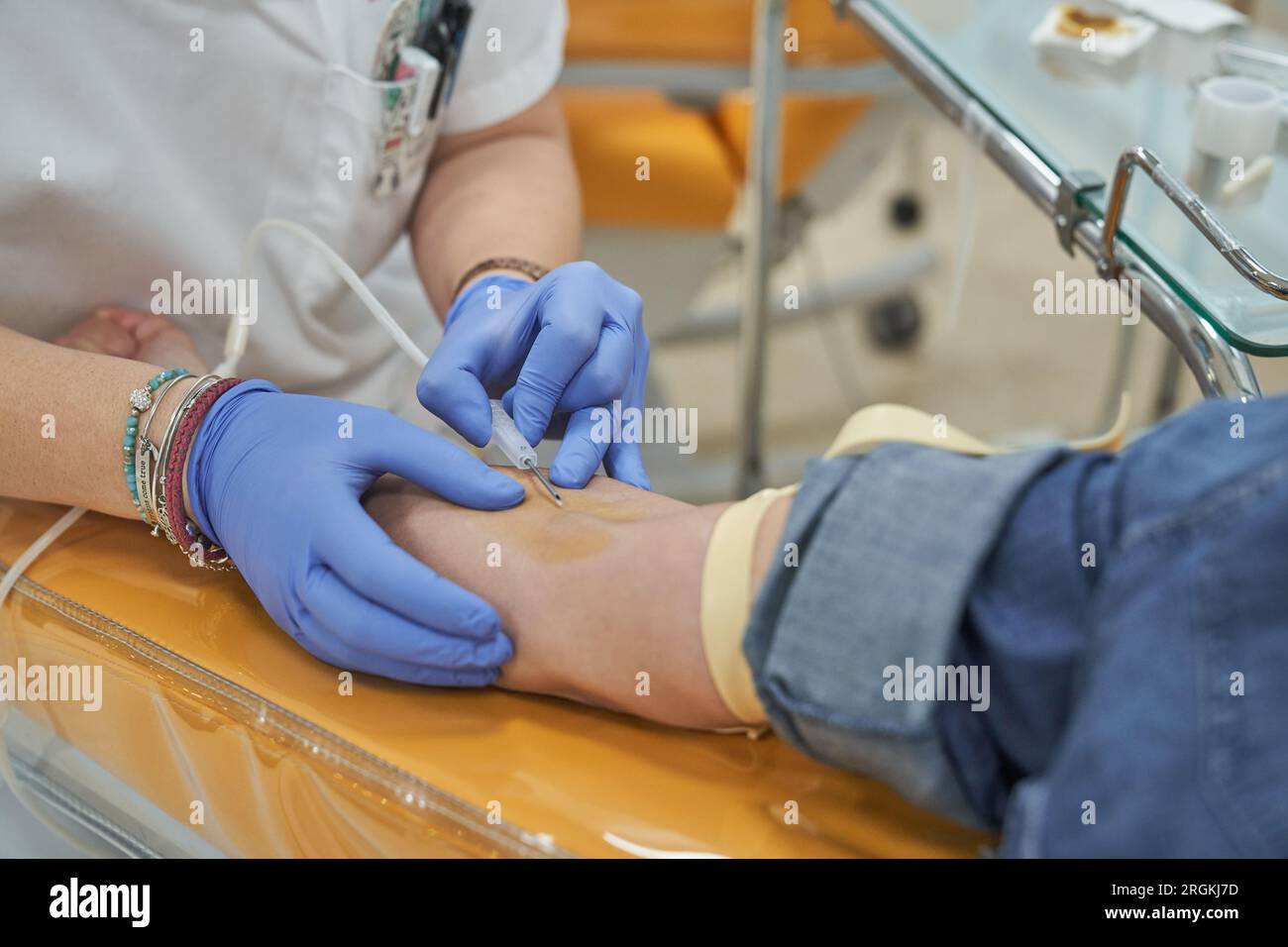 Unrecognizable female doctor in scrubs and gloves injecting needle in ...