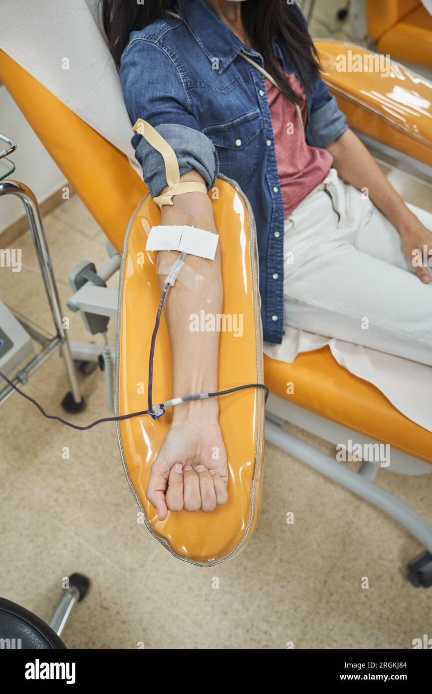From above of crop anonymous woman in denim jacket sitting in armchair ...