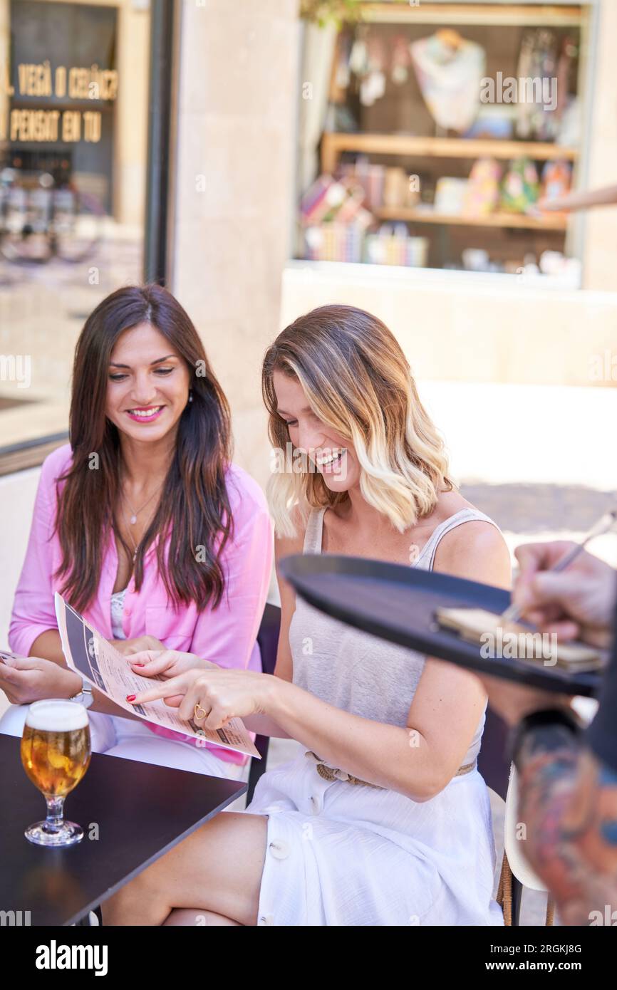 Crop waiter with tray and notepad taking order from smiling female ...