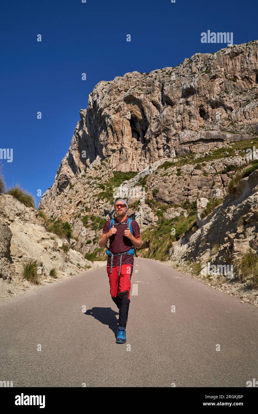 Full body of adult man with backpack observing rocky cliffs while ...