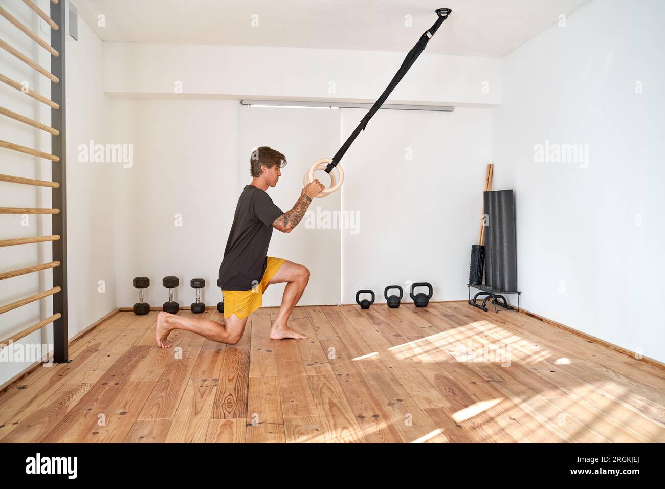 Full length of barefoot male athlete in sportswear standing on knee and ...