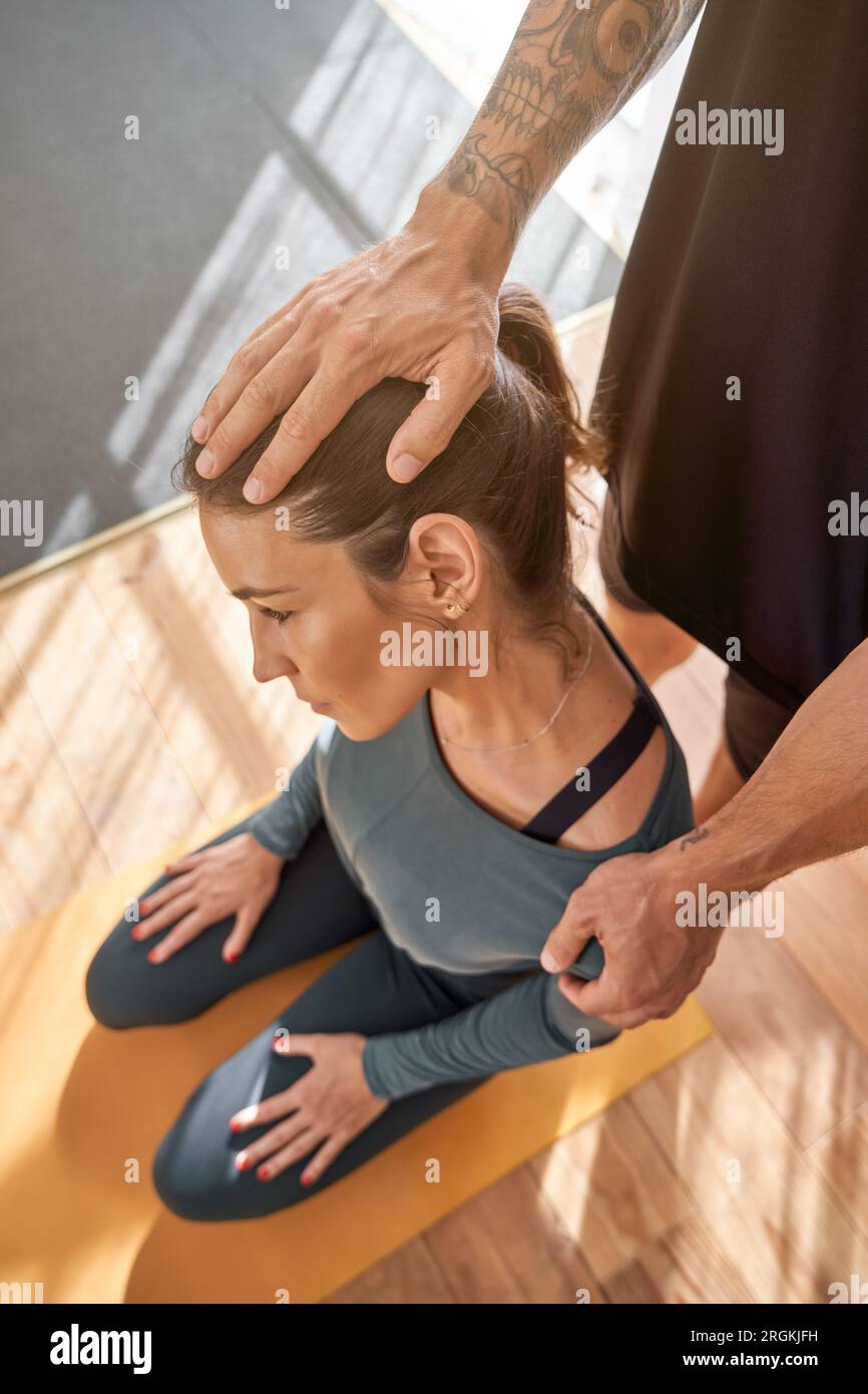 High angle of anonymous trainer touching head and shoulder of ethnic ...