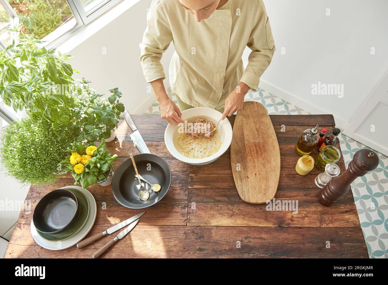From above crop woman in uniform mixing ingredients for steak tartare ...