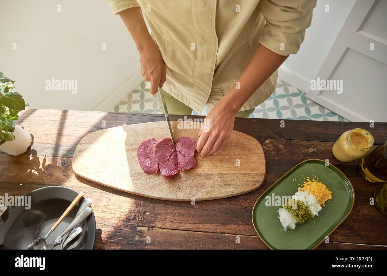 Top view of professional female chef cutting beef with knife in process ...