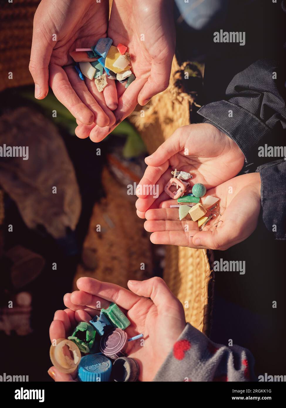Top view of hands of crop anonymous people holding pieces of plastic ...
