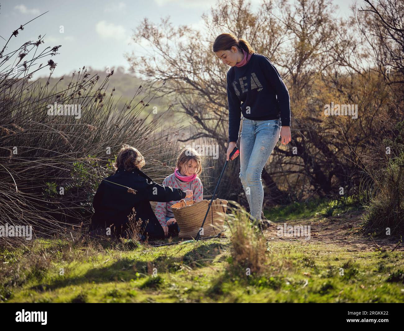 Side view of teen girl looking for rubbish and plastic waste with trash ...