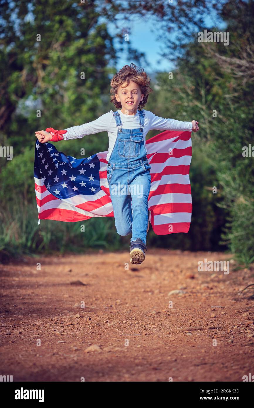 Full body of energetic boy with colorful waving American flag running ...