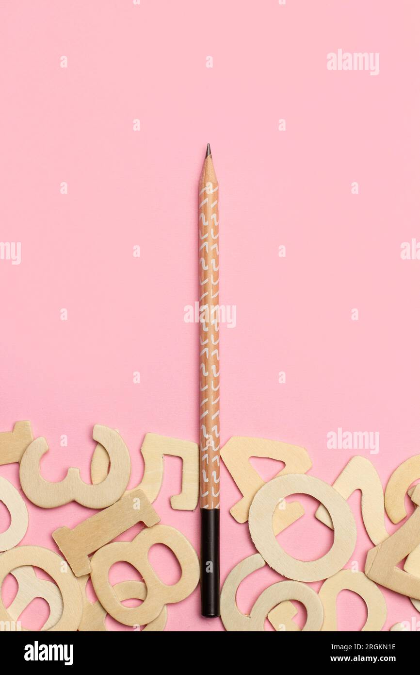 A black wooden pencil and wooden numbers on a pink background with copy ...