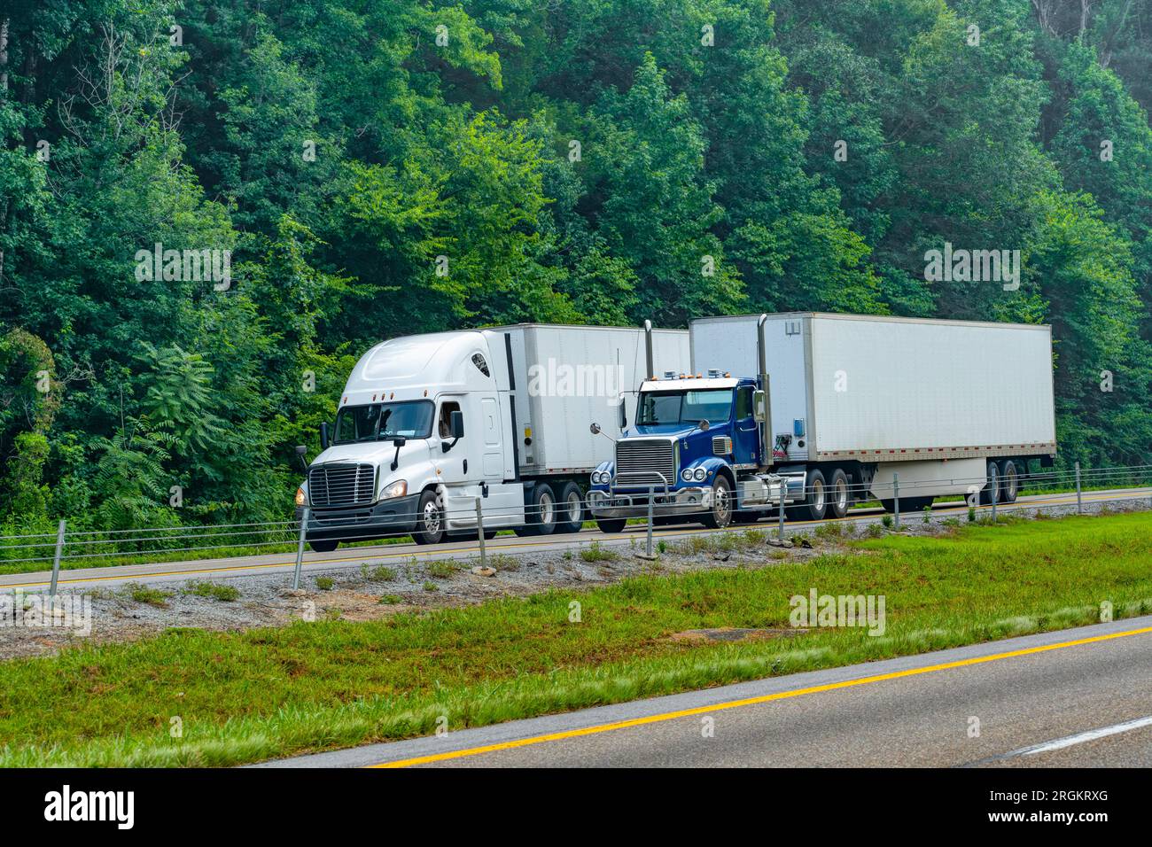 Horizontal shot of two eighteen-wheelers traveling down an interstate ...