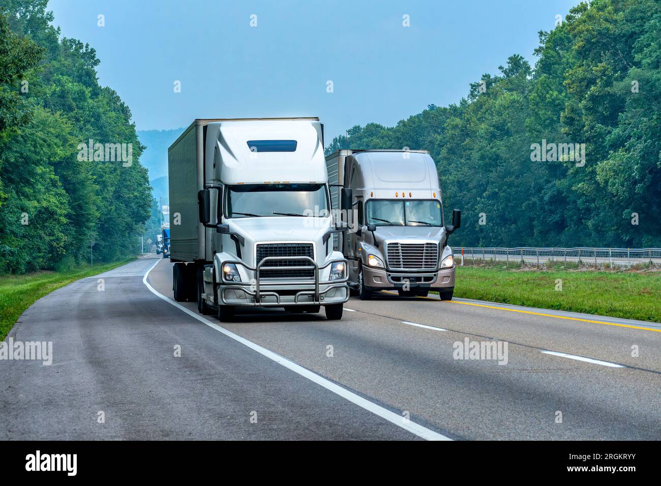 Horizontal shot of two semi trucks on the interstate with light traffic ...