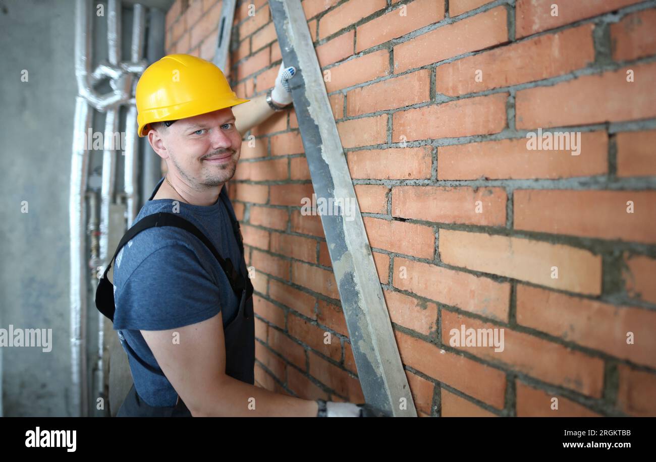 Portrait of constructor making brick wall smooth in order to plastering ...