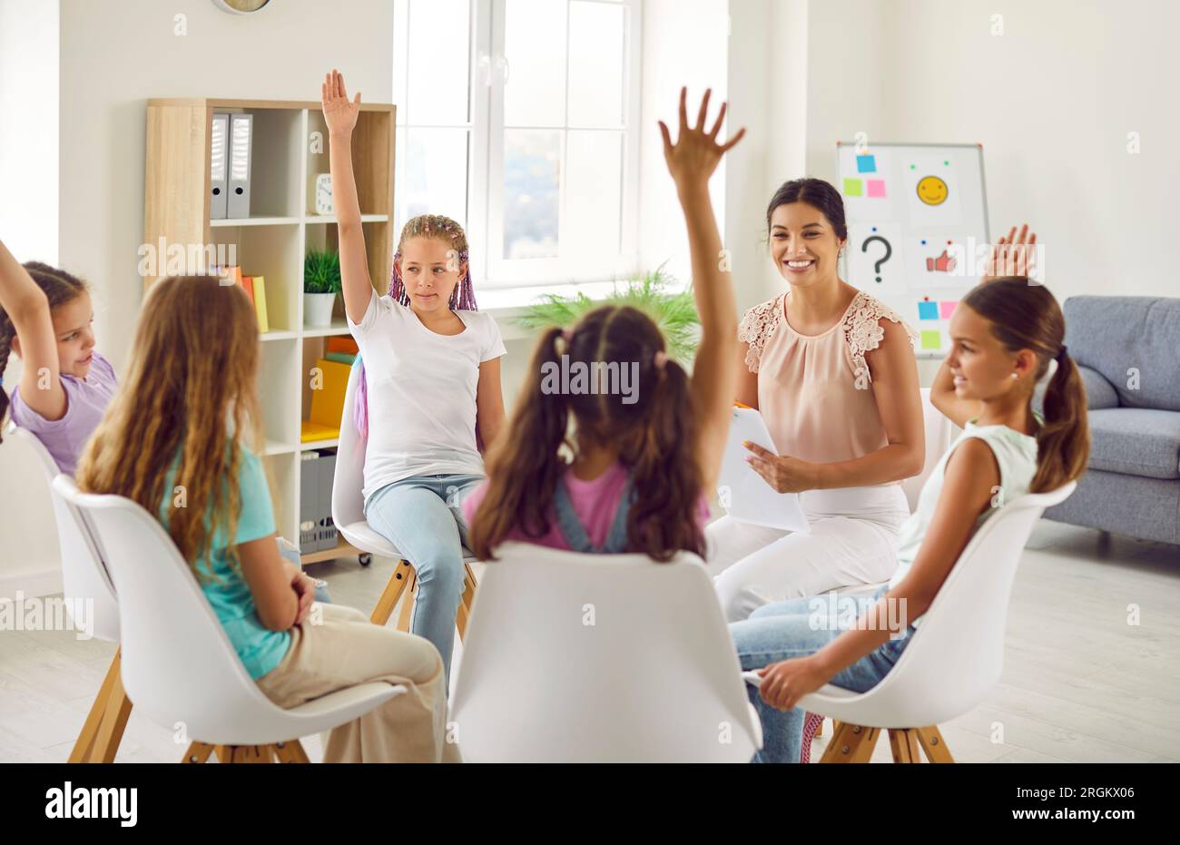 Group of school children girls sitting in a circle with psychologist ...