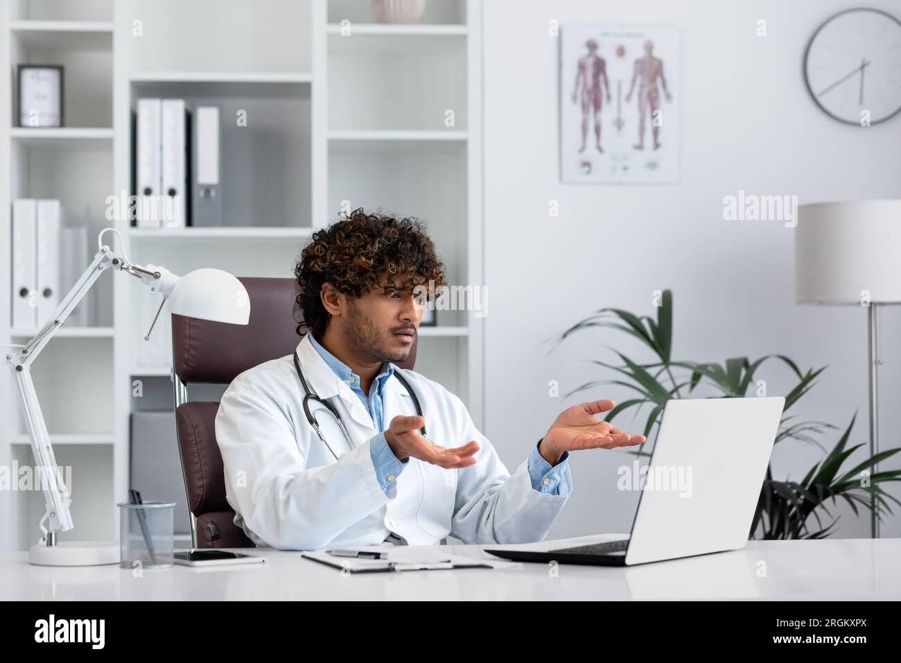 Young indian displeased and serious doctor inside office workplace ...