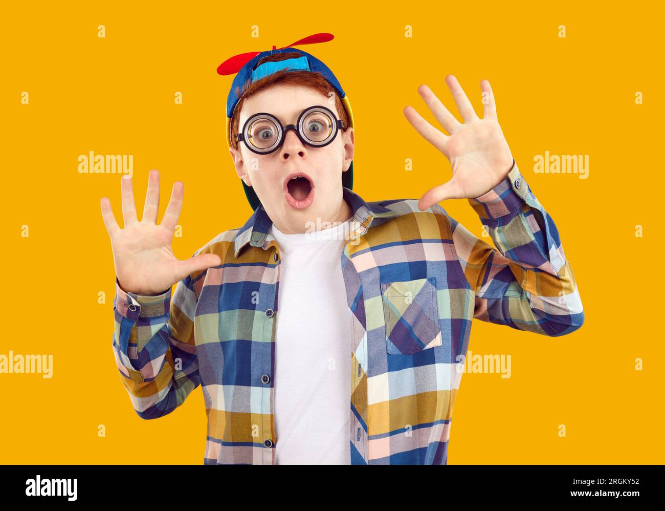 Little boy in round glasses and funny propeller cap looking at camera ...