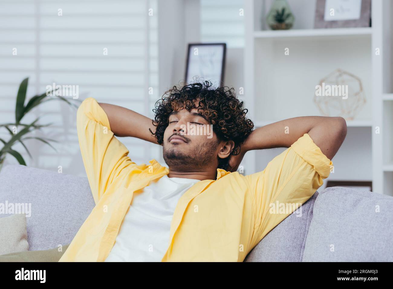 Young man relaxing alone at home on sofa, close-up Hispanic man with ...
