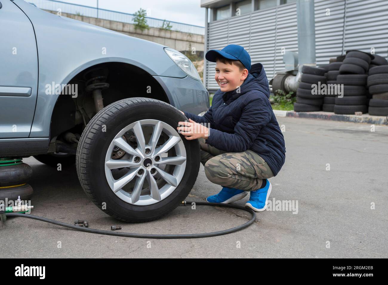 The boy helps at a car service. Replacing the wheels on the car, the ...
