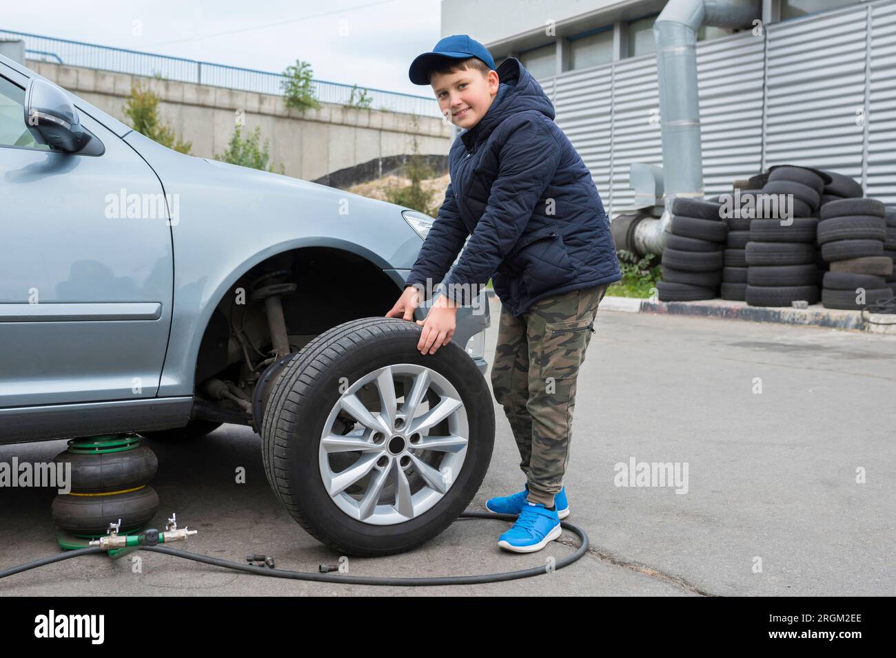 Children's auto mechanic changes the wheel on a car. Replacing wheels ...