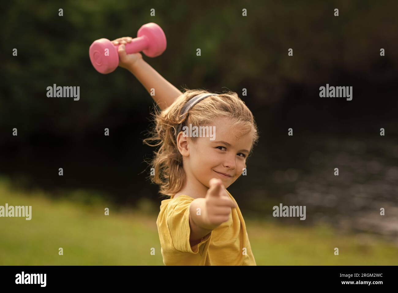 Sport activities at leisure with children. Blonde boy holding dumbbells. Sports exercises for ...