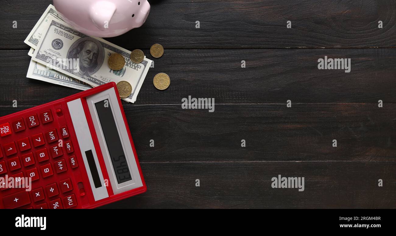 Calculator, piggy bank and money on black wooden background with space ...