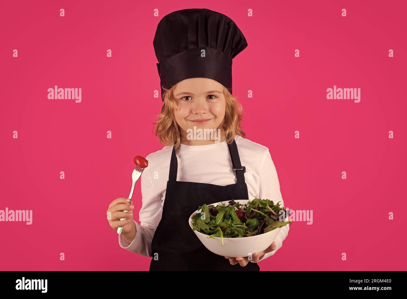 Kid cook hold plate with vegetables and fork with tomato. Portrait of ...