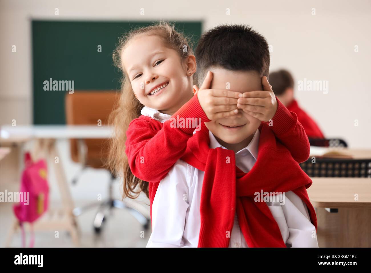 Little girl closing her classmate's eyes in classroom Stock Photo - Alamy