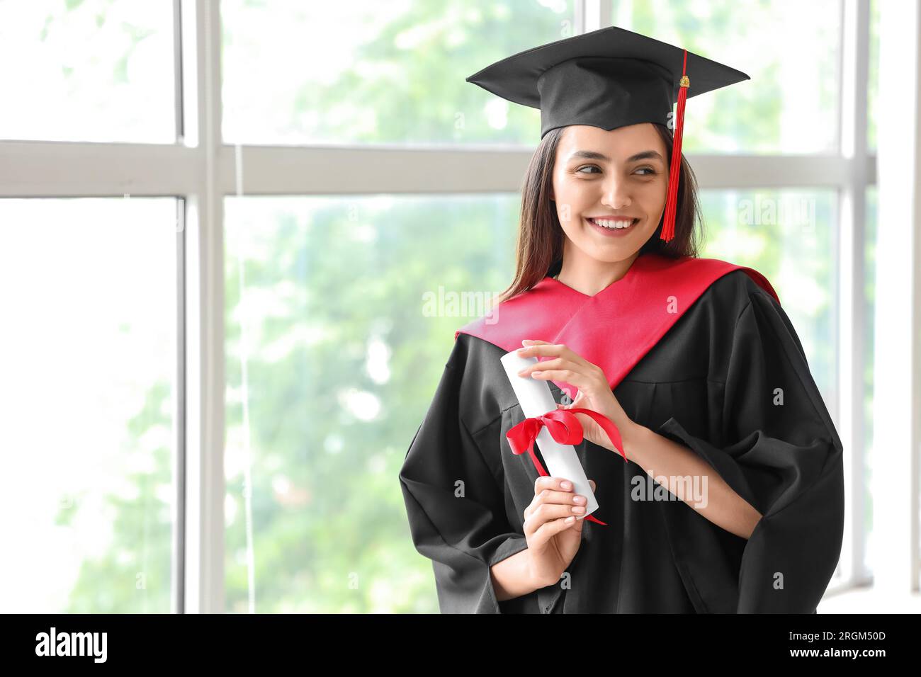 Female graduate student with diploma near window in room Stock Photo ...