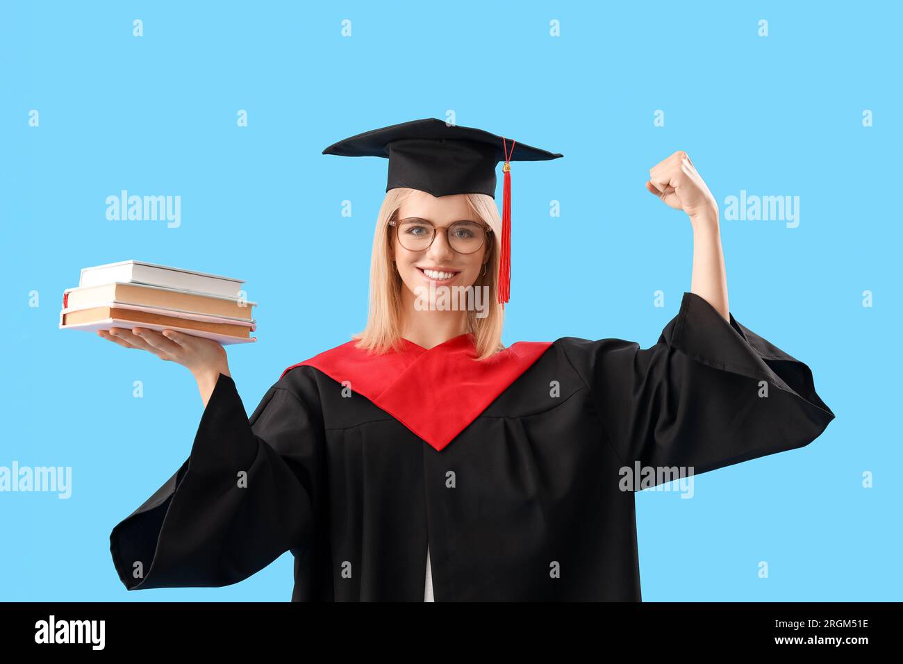 Female graduate student with books showing muscles on blue background ...